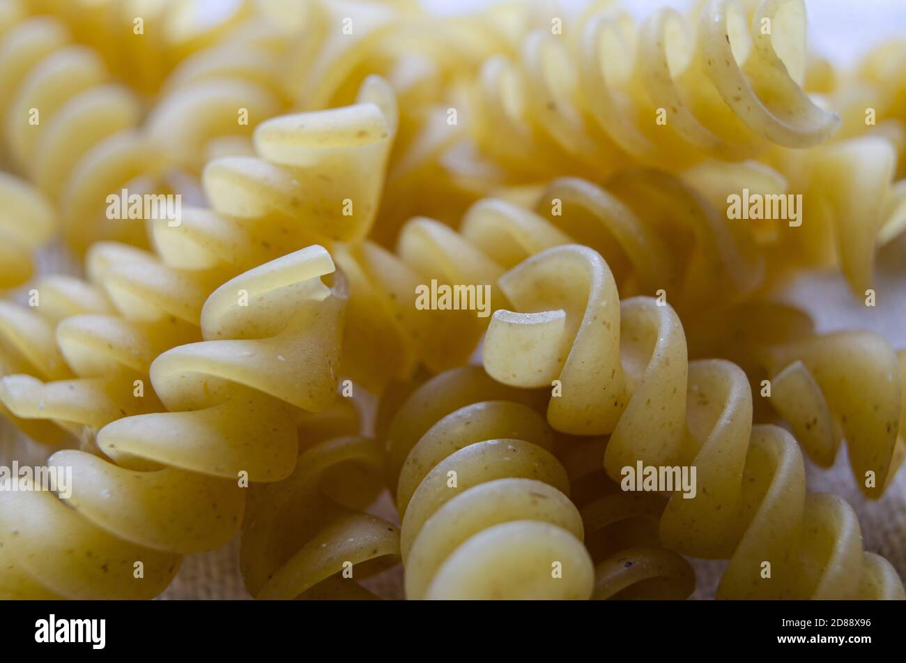 Closeup of uncooked rotini pasta on a white surface Stock Photo - Alamy