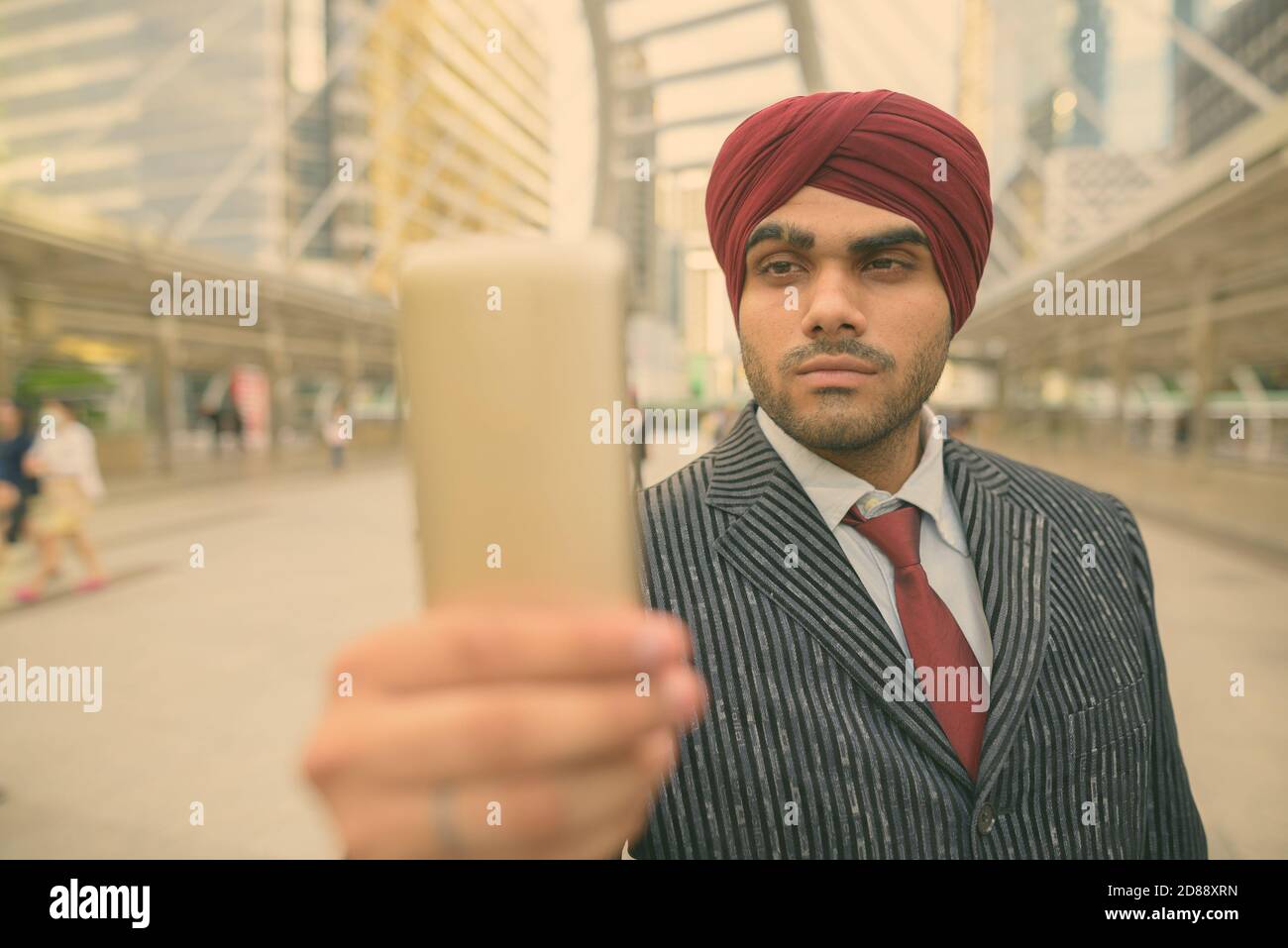 Young handsome Indian Sikh businessman wearing turban while exploring ...