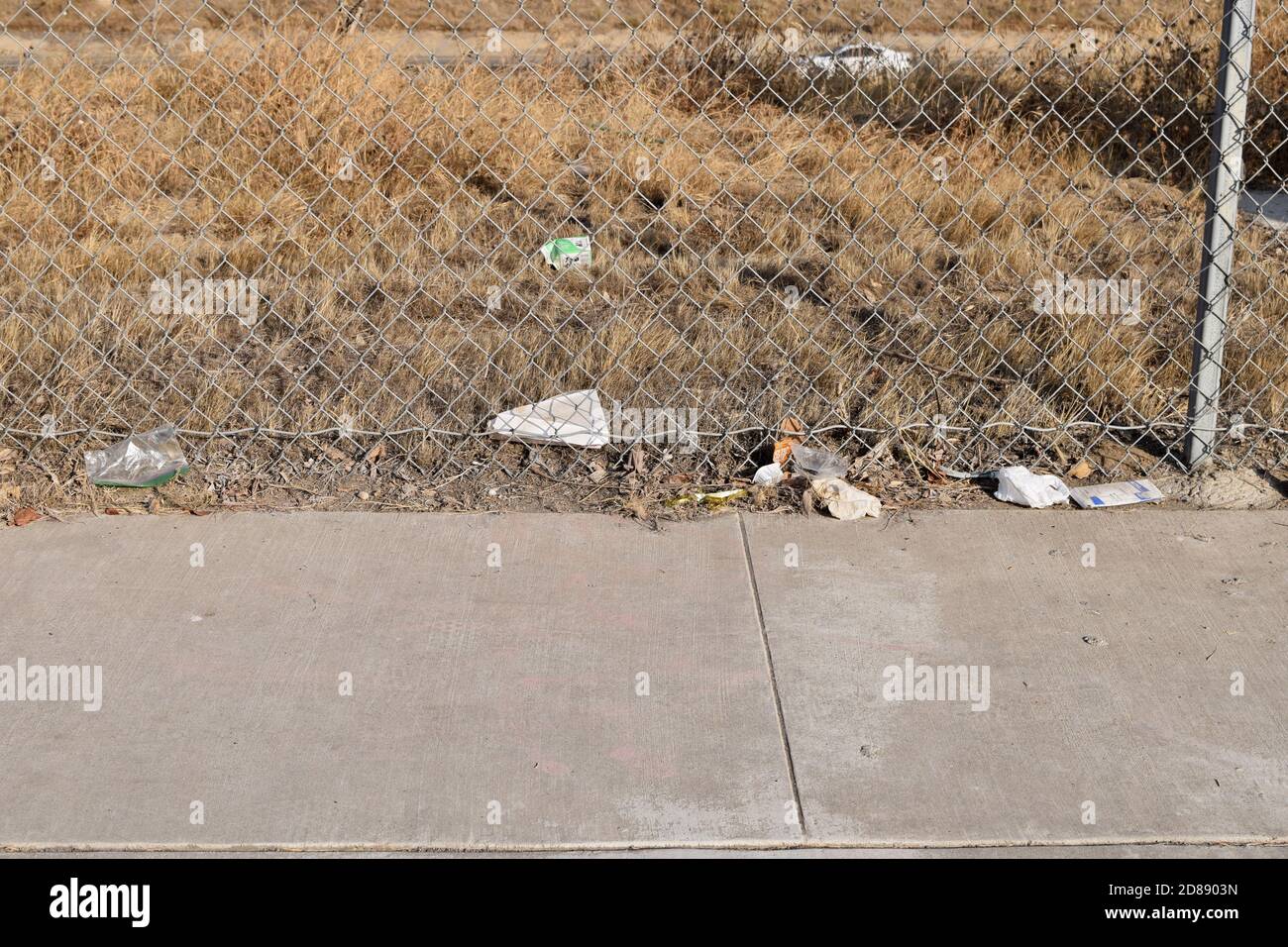 Fence separating the footpath and a grassy area with trash Stock Photo ...
