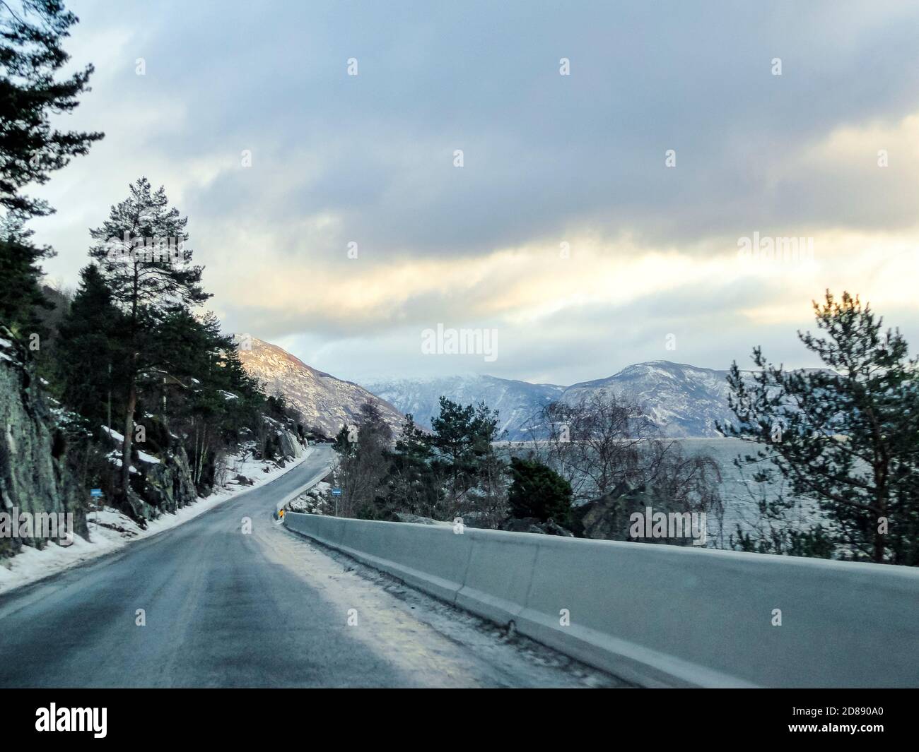 Driving at sunrise through mountains and fjords in Norway. Black ice on ...