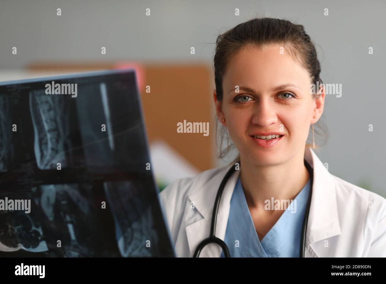 Doctor neurologist holds in hand an x ray of spine in clinic portrait ...