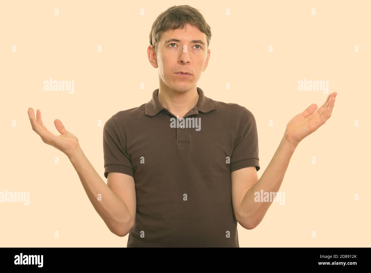 Studio shot of man looking confused with both arms raised Stock Photo ...