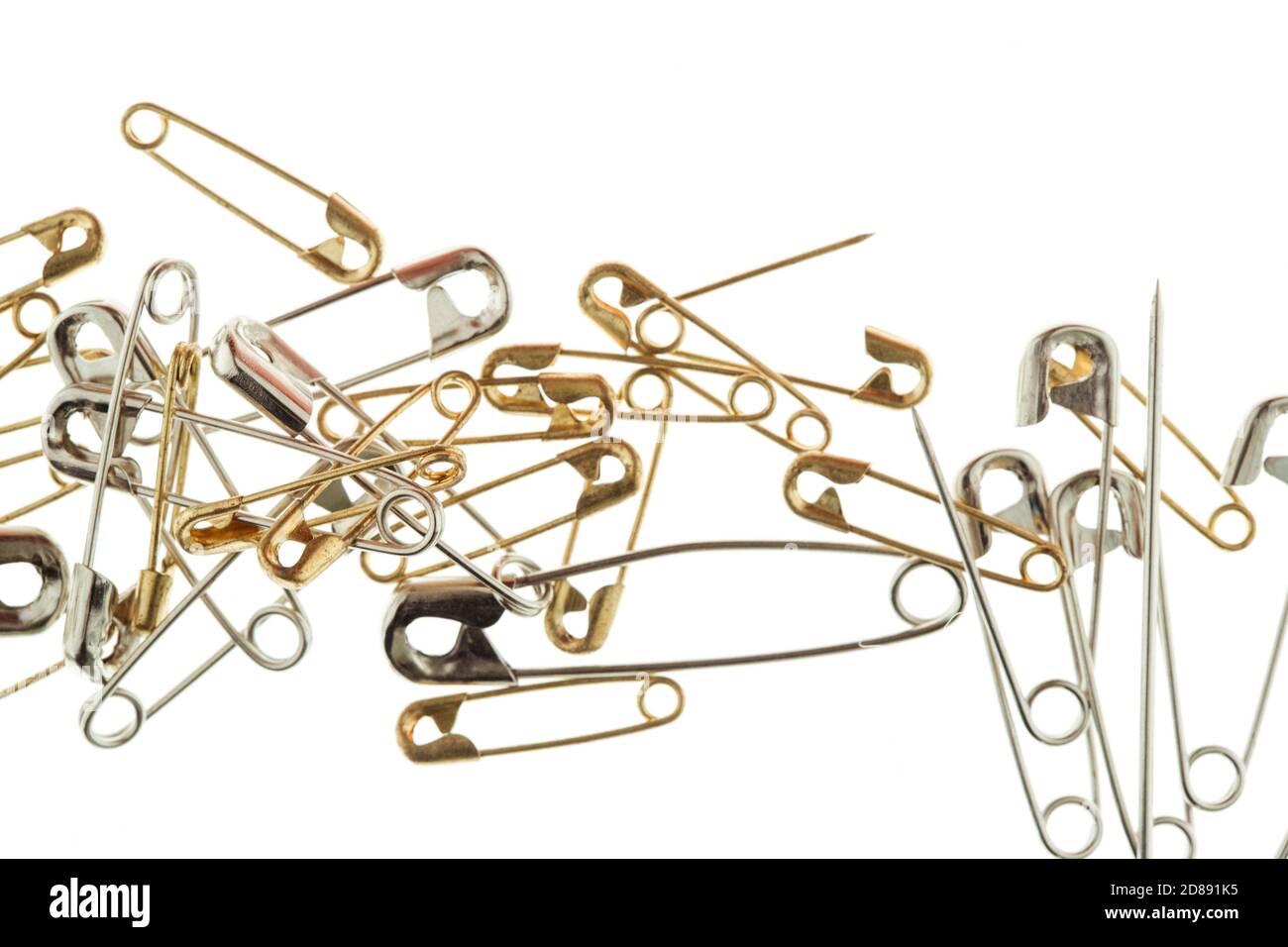 A directly above shot of a pile of metal safety pins on a white ...