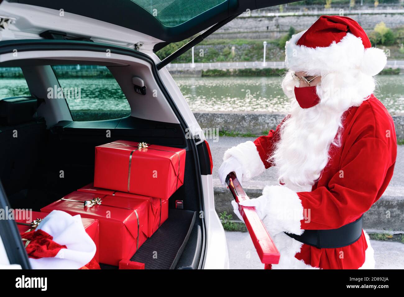 Portrait of Santa Claus with the trunk of the car open full of gifts ...
