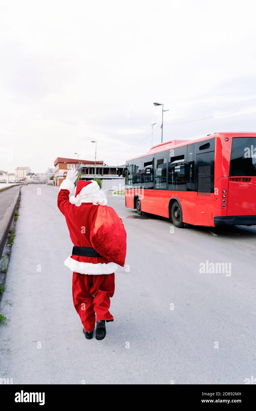 Back portrait of Santa Claus running around worried and calling a bus ...