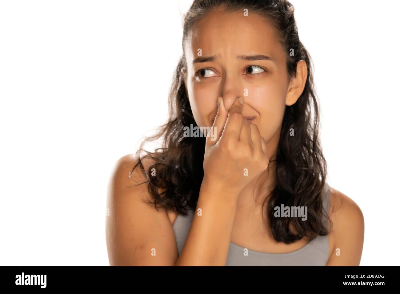 portrait of young woman closing the nose with her fingers on white ...