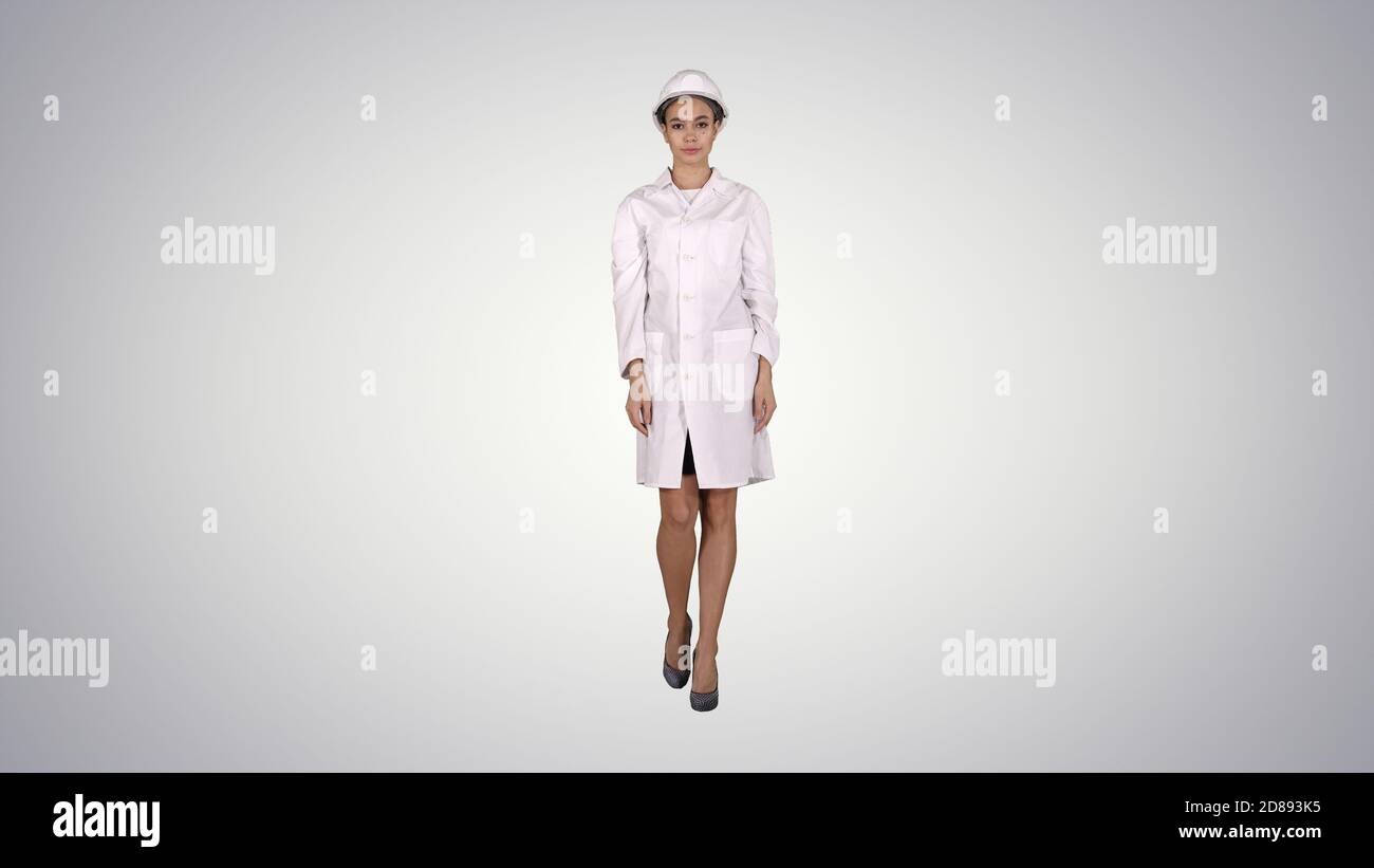 Woman engineer in white robe and white hard hat walking on gradi Stock ...