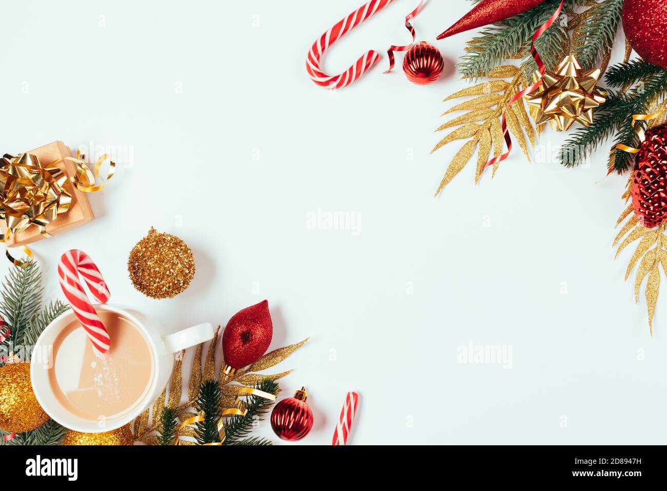Christmas flat lay frame with cup of coffee, candy canes, fir branches, red and golden baubles ...