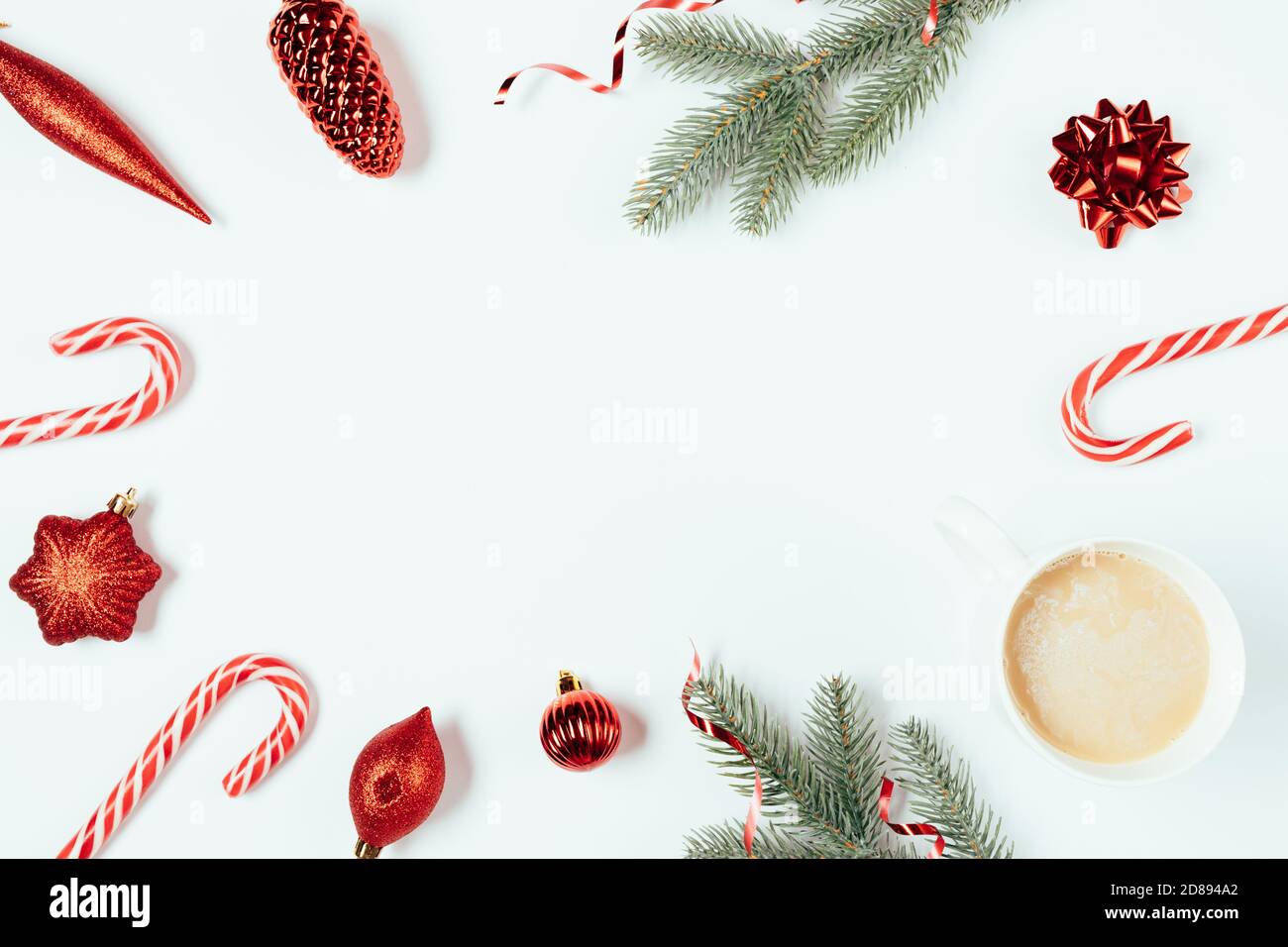 Christmas flat lay frame with green fir branches, red decorations, candy canes and cup of coffee ...