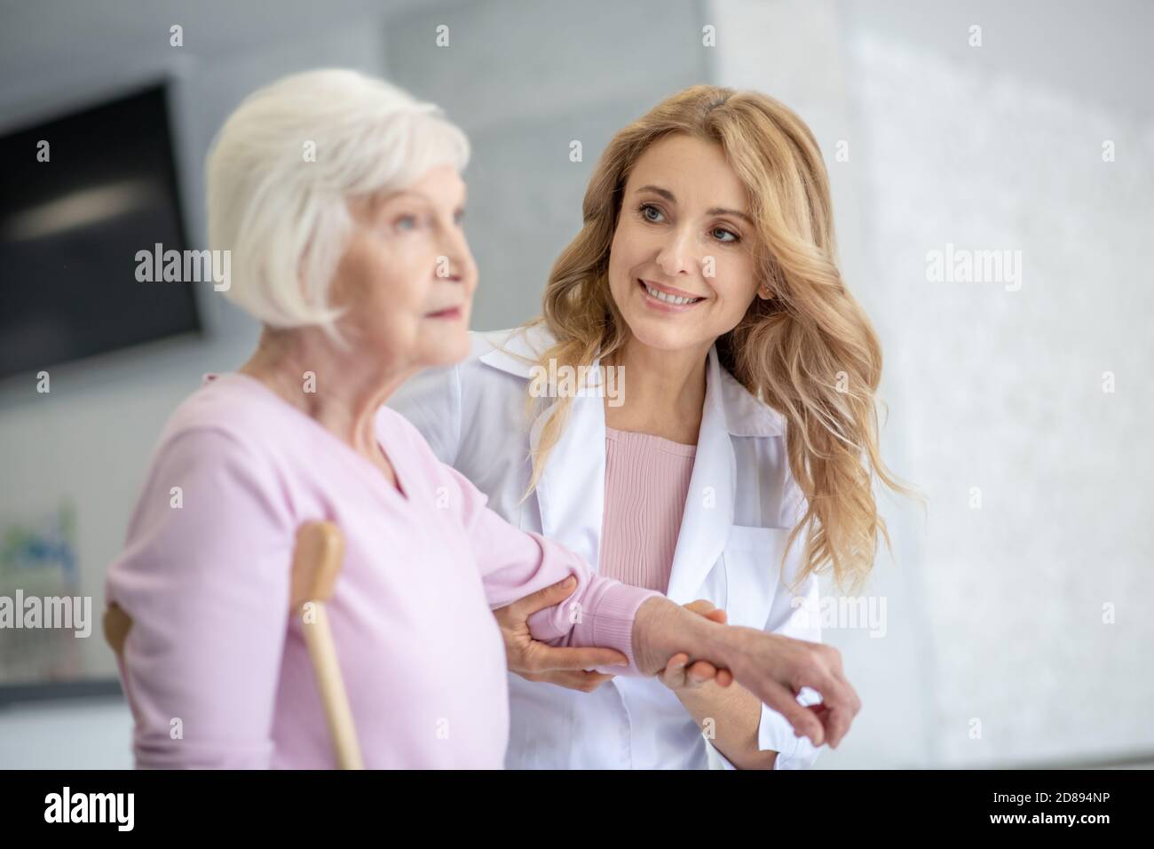 Doctor in a lab coat supporting her patient and looking at her Stock ...