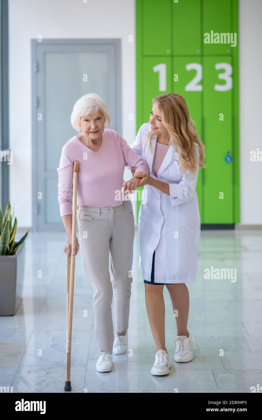 Doctor in a lab coat and a patient walking together in a corridor Stock ...