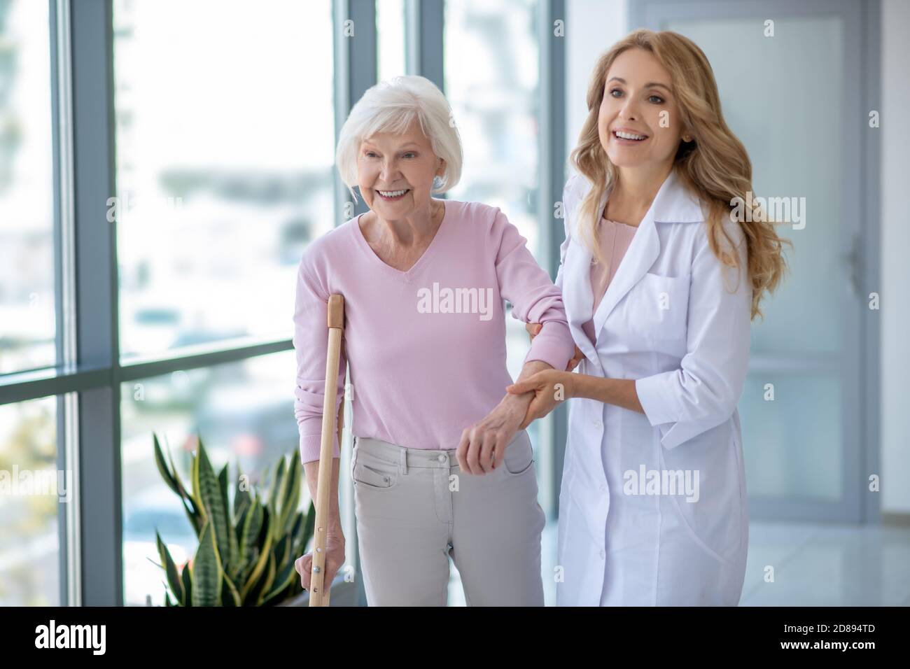 Doctor in a lab coat and a patient walking together and looking ...