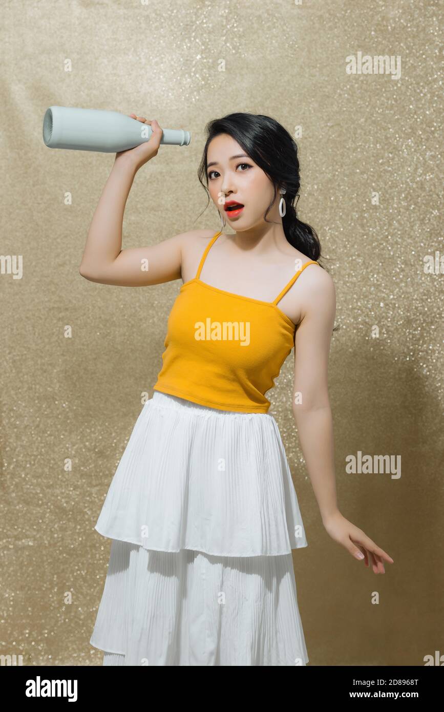 Portrait of sweet, gorgeous young Asian woman with bottle of beverage ...