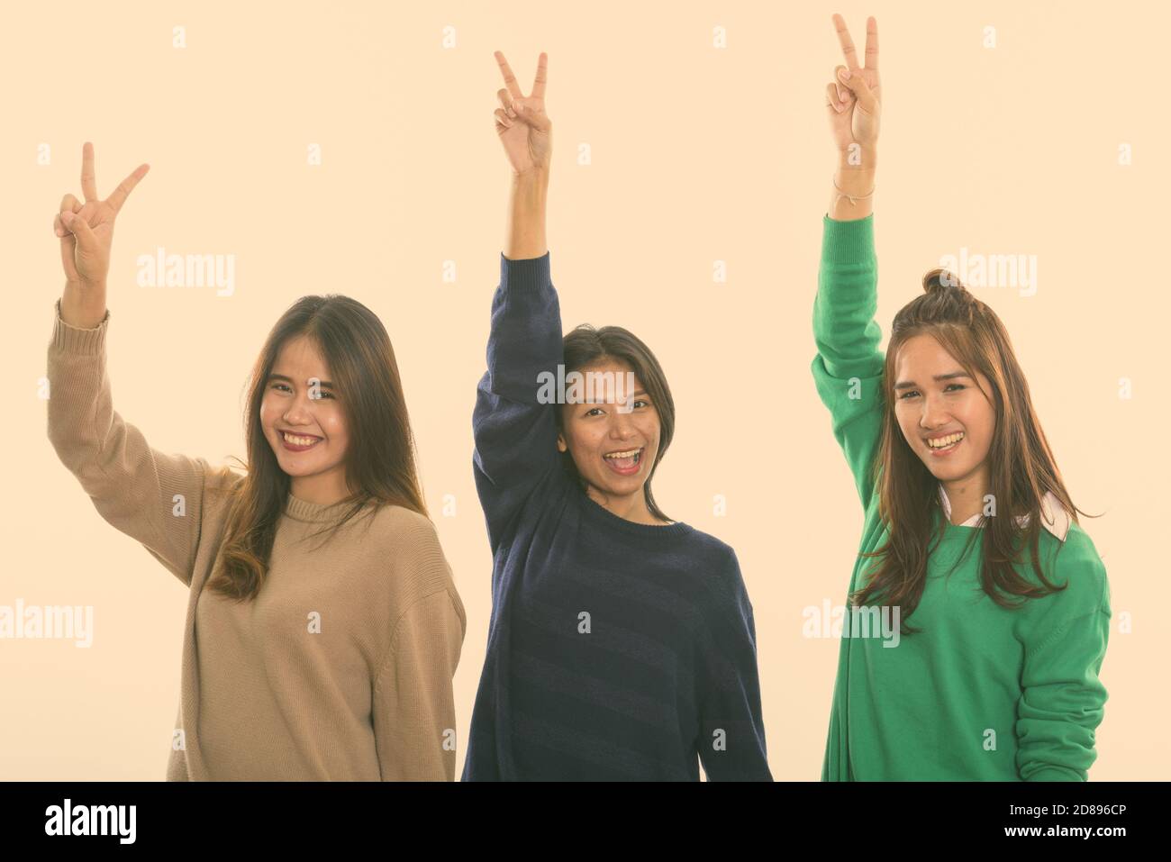 Studio shot of three happy young Asian woman friends smiling while ...