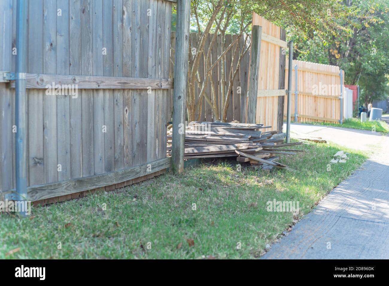 Concrete back alley with old fence near new lumber boards pickets at ...
