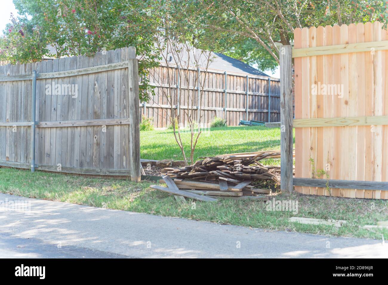 Concrete back alley with old fence near new lumber boards pickets at ...