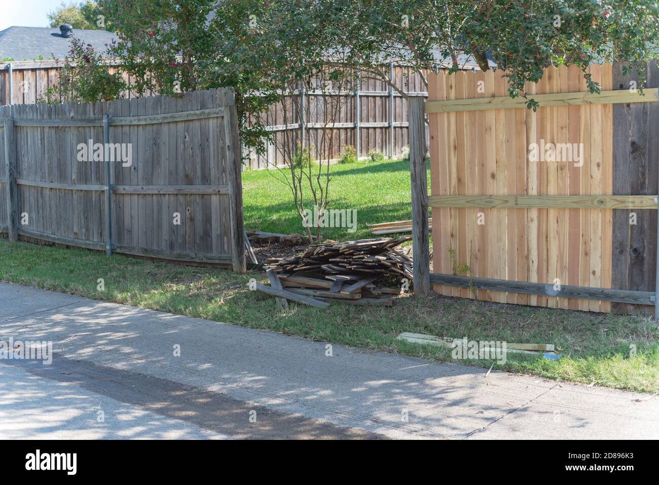 Concrete back alley with old fence near new lumber boards pickets at ...