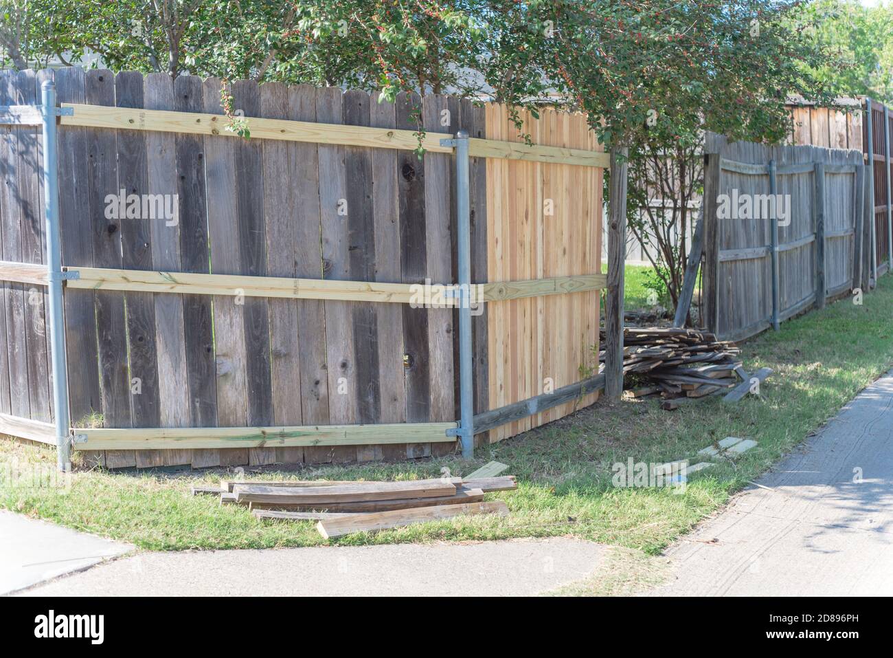 Concrete back alley with old fence near new lumber boards pickets at ...