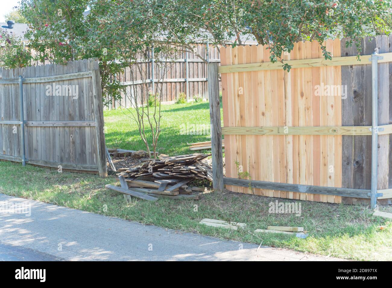 Concrete back alley with old fence near new lumber boards pickets at ...
