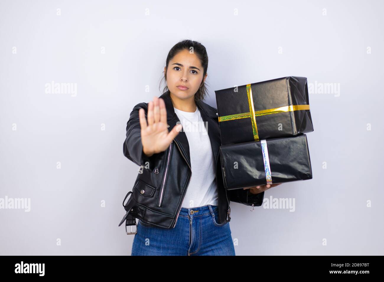 Young beautiful woman holding gifts over isolated white background ...