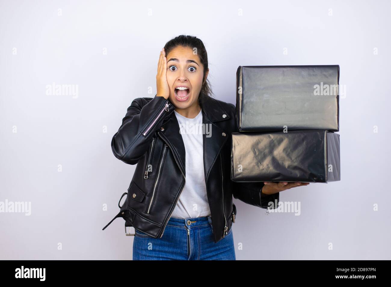 Young beautiful woman holding gifts over isolated white background ...