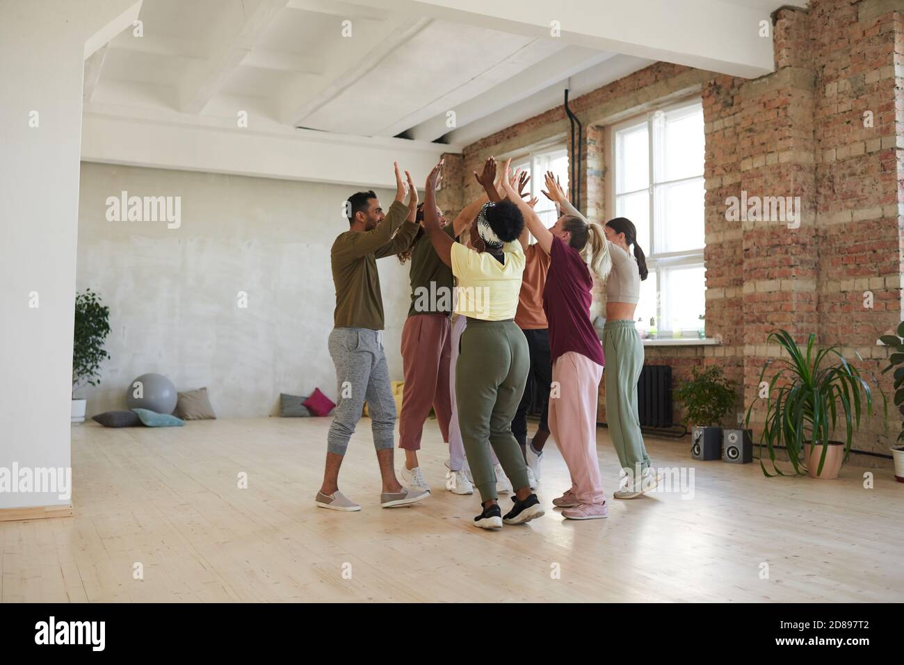 Group of dancers giving high five to each other during training in ...