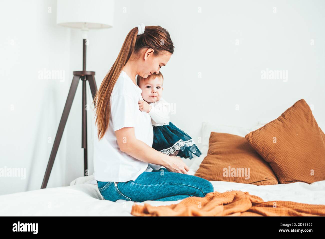 Mom and baby are at home on the bed and hug Stock Photo - Alamy