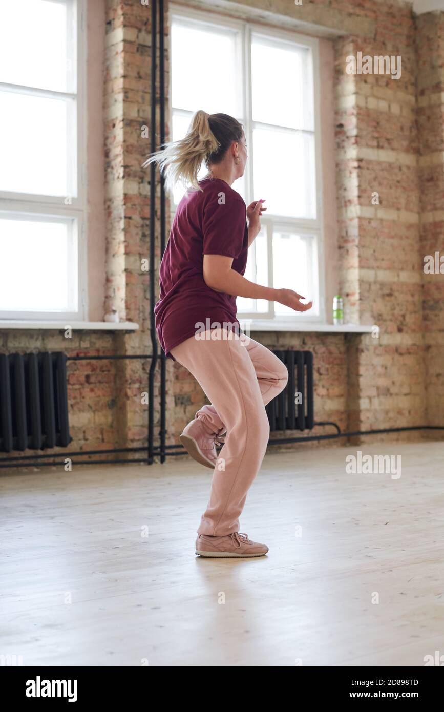 Rear view of young dancer in sports clothing dancing alone in dance ...