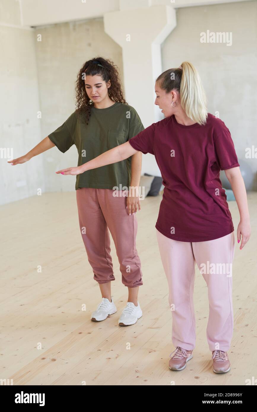 Young dance instructor showing the movement to woman and teaching her ...