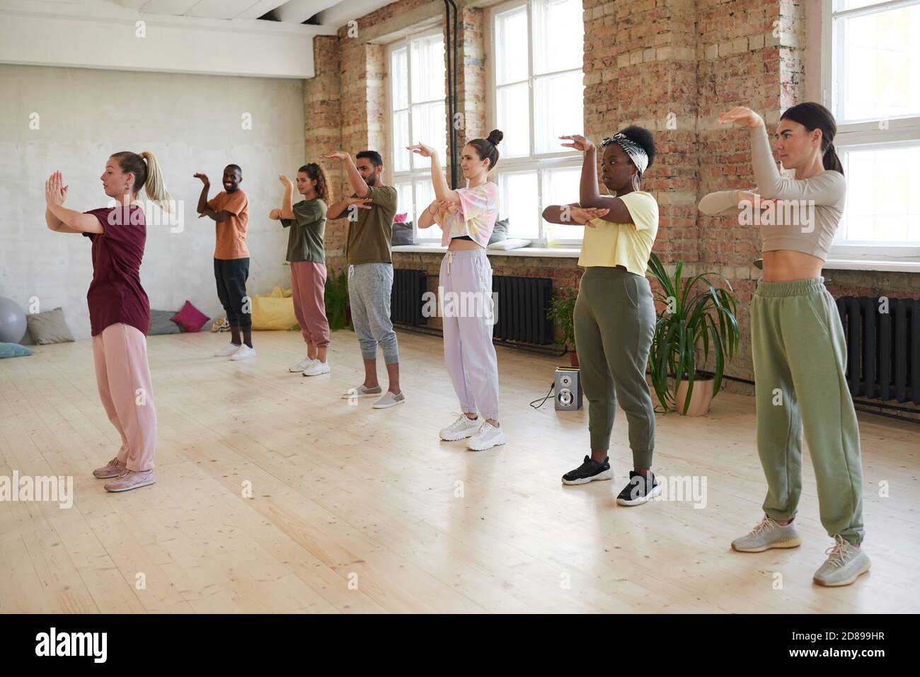 Group of young people standing and repeating the movements of the ...