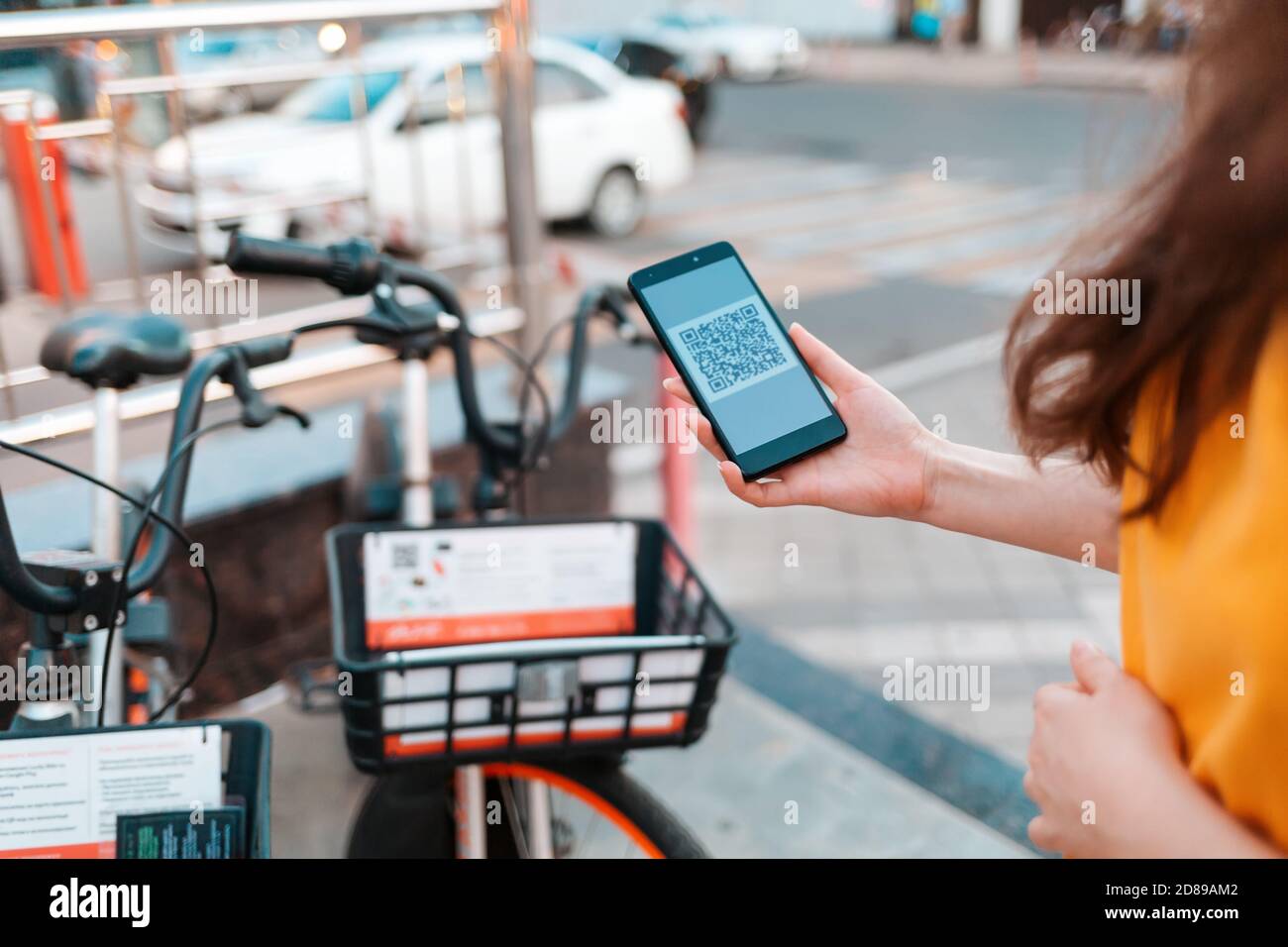 Bike rental on the street. A woman scans a qr code on a Bicycle using a ...