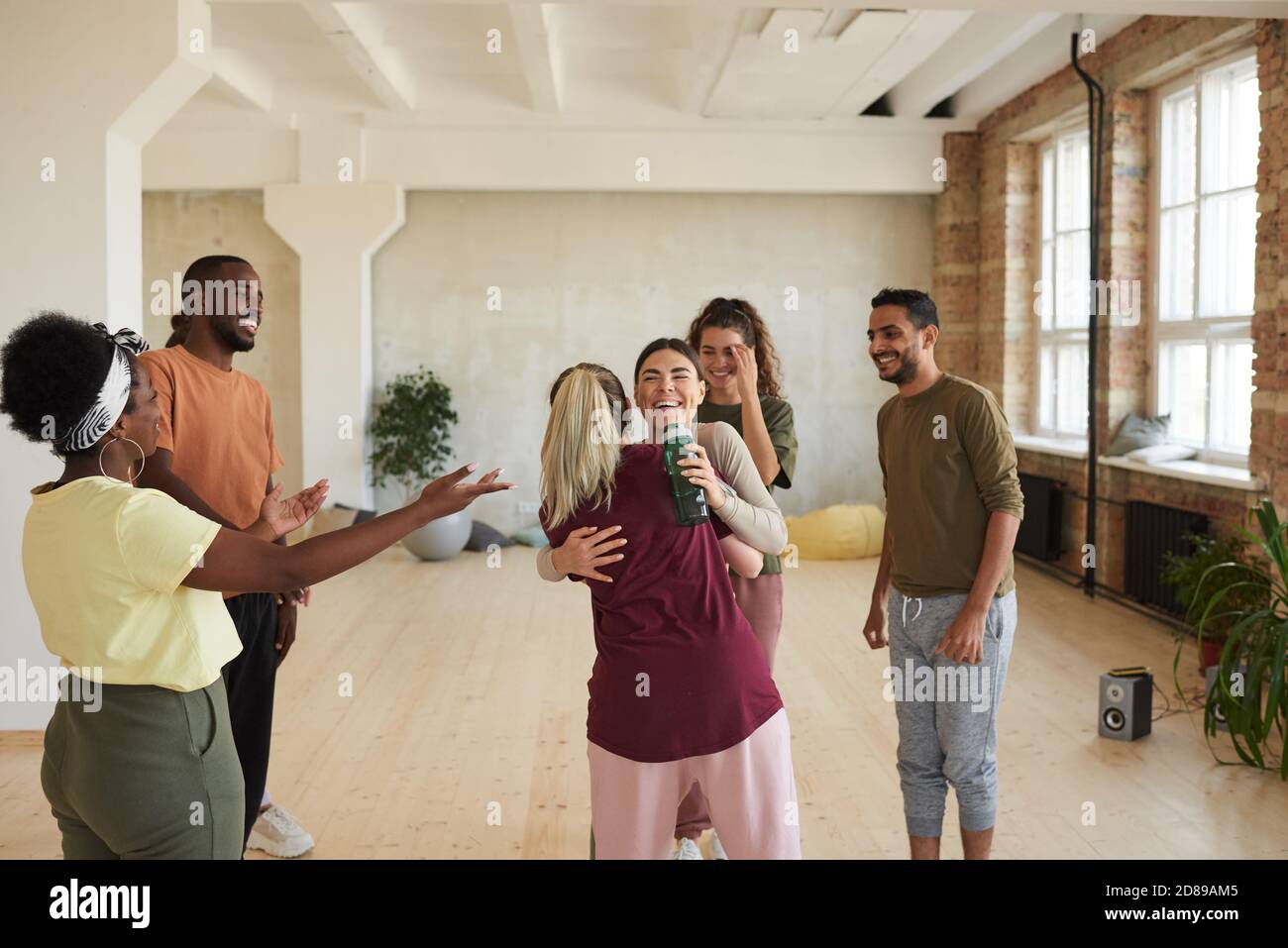 Group of young happy people greeting each other embracing and talking ...