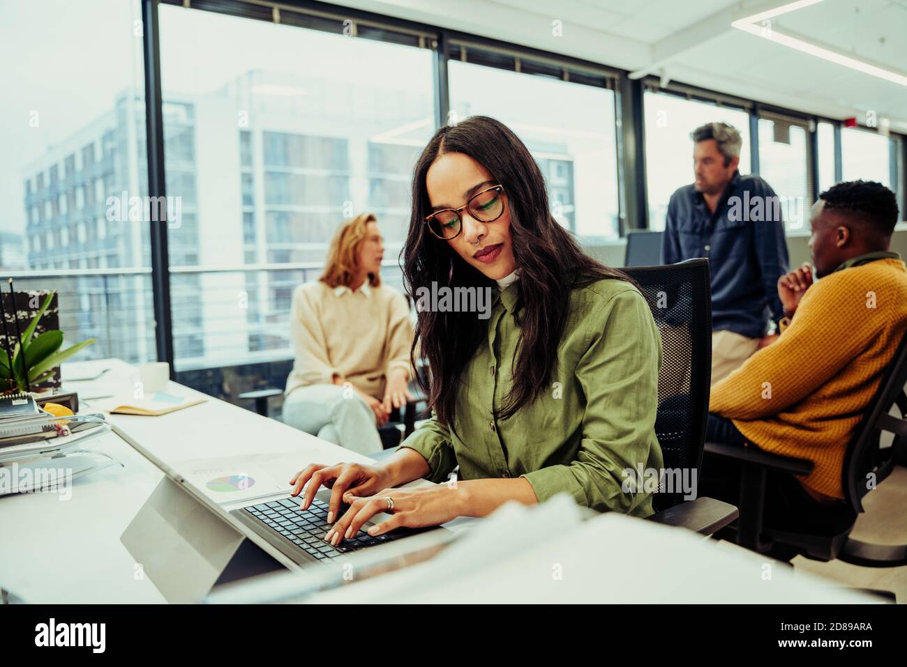 Mixed race business woman typing on keypad researching digital designs ...