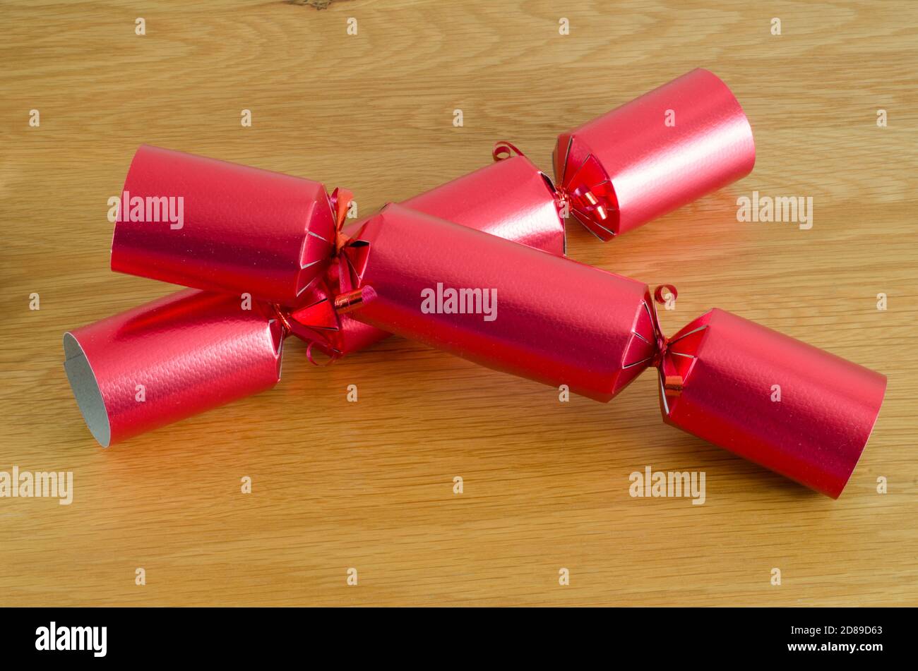 A pair of red foil Christmas crackers tied with ribbons laying on an ...