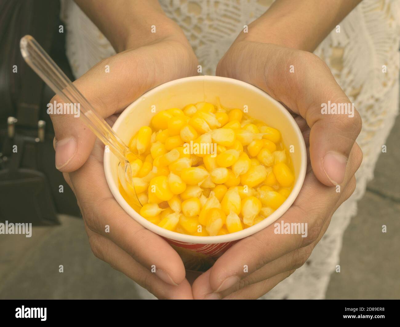 Hands of young woman holding cup of deliciously steamed sweet corn ...