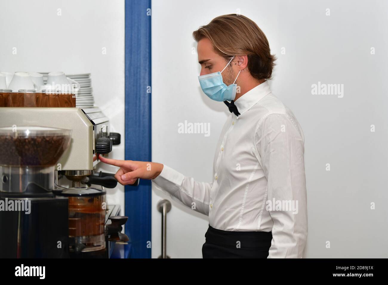 Focused young male bartender wearing a surgical mask operating a bar ...