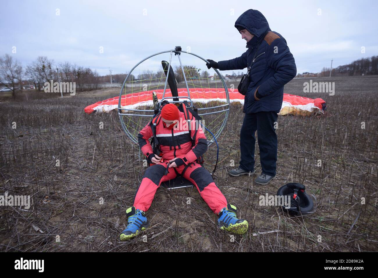 Paramotoring. Instructor starting the engine of paramotor by turning ...