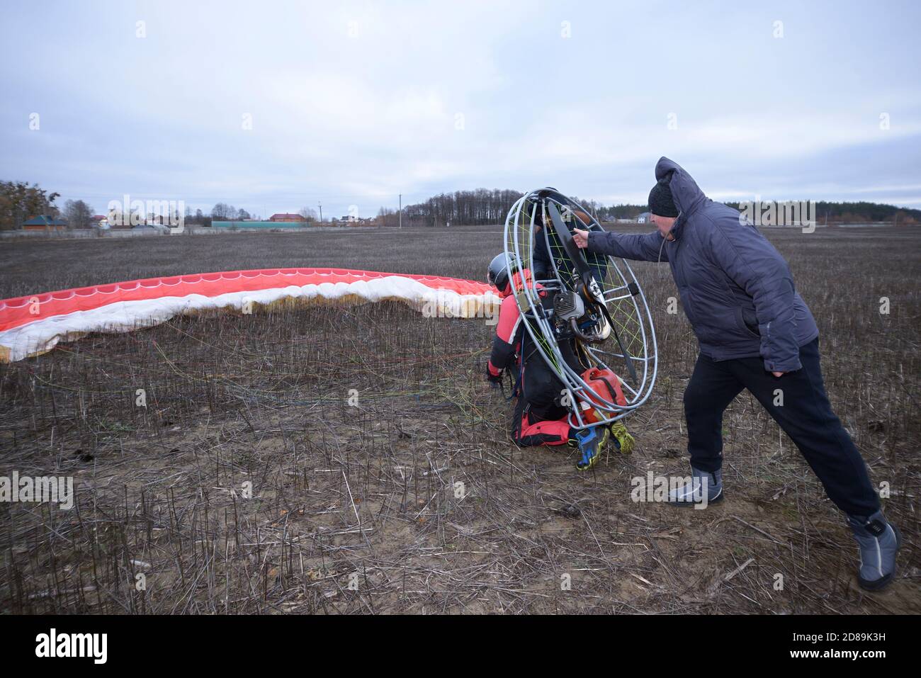 Paramotoring. Instructor starting the engine of paramotor by turning ...