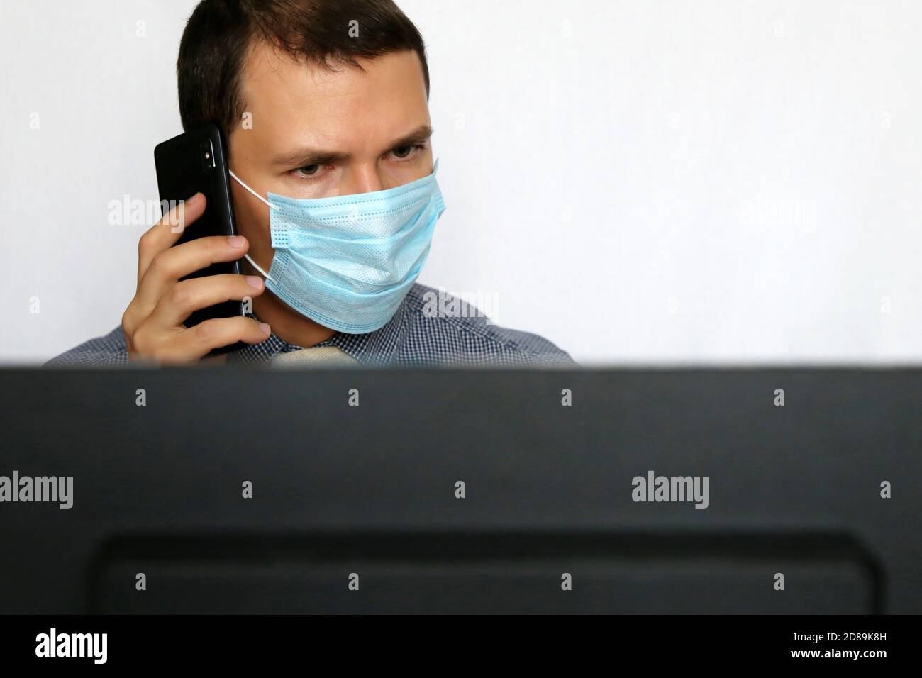 Man in face mask and office clothes talking on mobile phone in front of ...