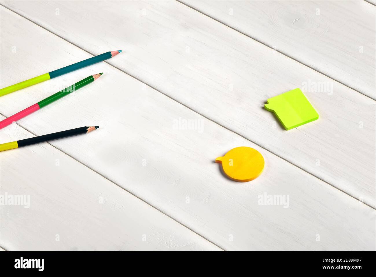 Colorful double-sided pencils, orange and yellow sticky notes on white ...