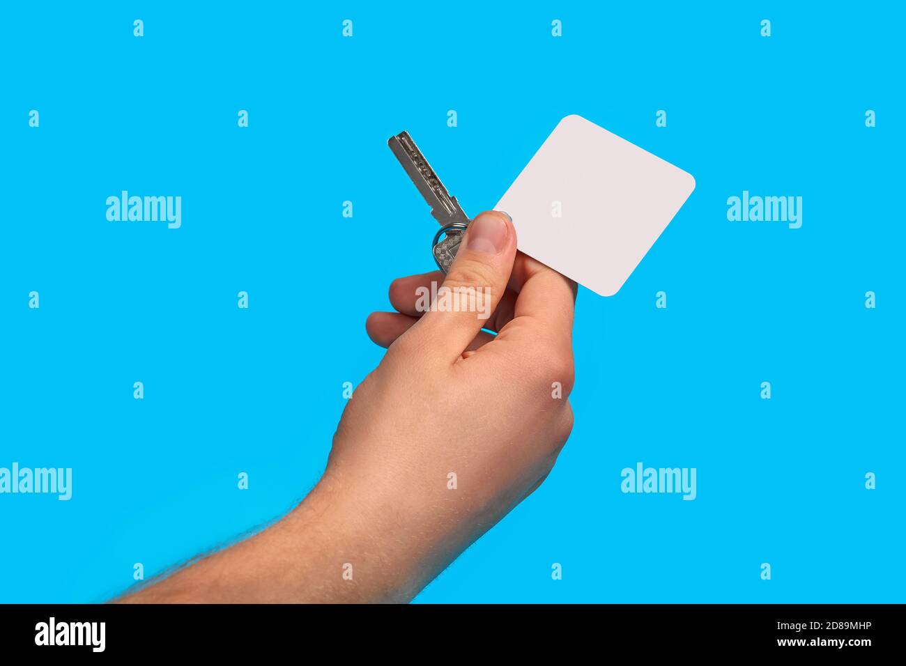 Hand of unrecognizable guy is holding a key with empty white square ...