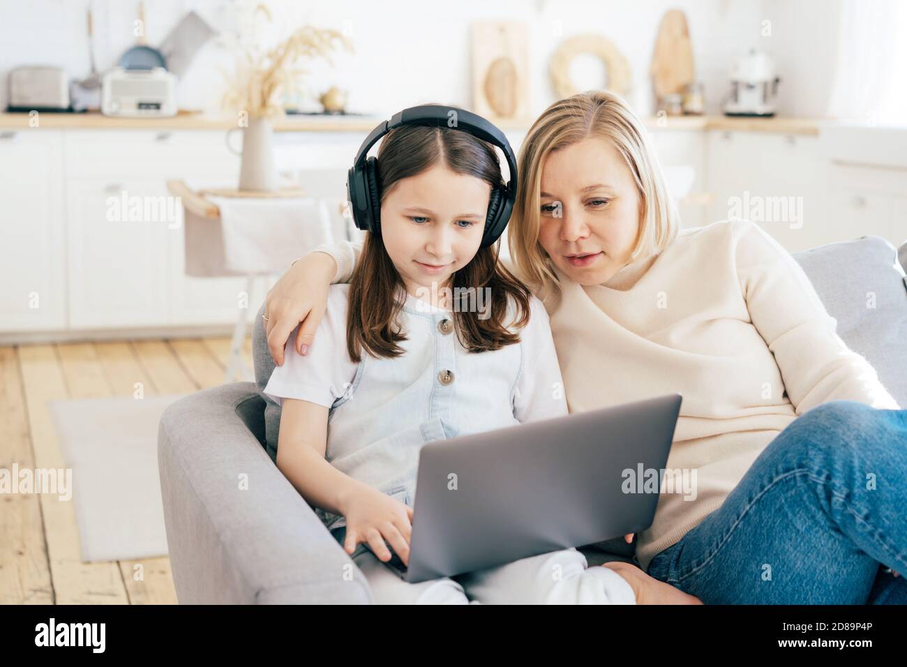 Mom and daughter are looking at the laptop screen and smiling Stock ...
