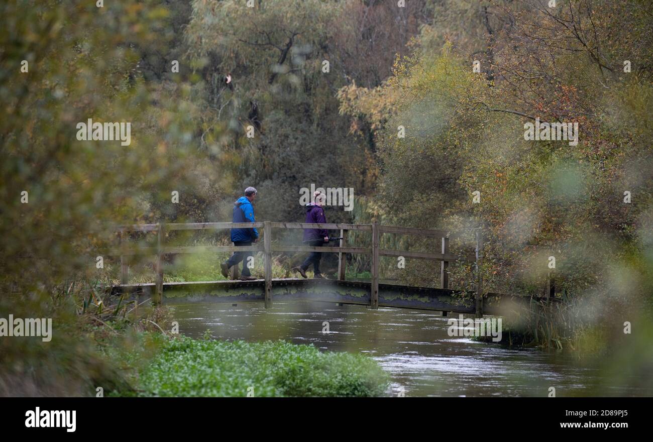 People walk across a bridge over the river Itchen near to Ovington in ...