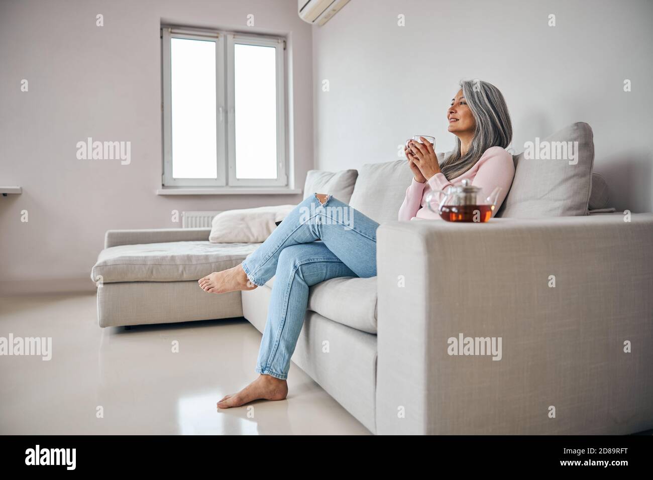 Beautiful woman sitting on couch and drinking tea at home Stock Photo ...