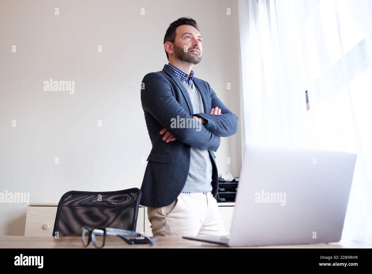 Portrait of confident business man standing in office with computer ...