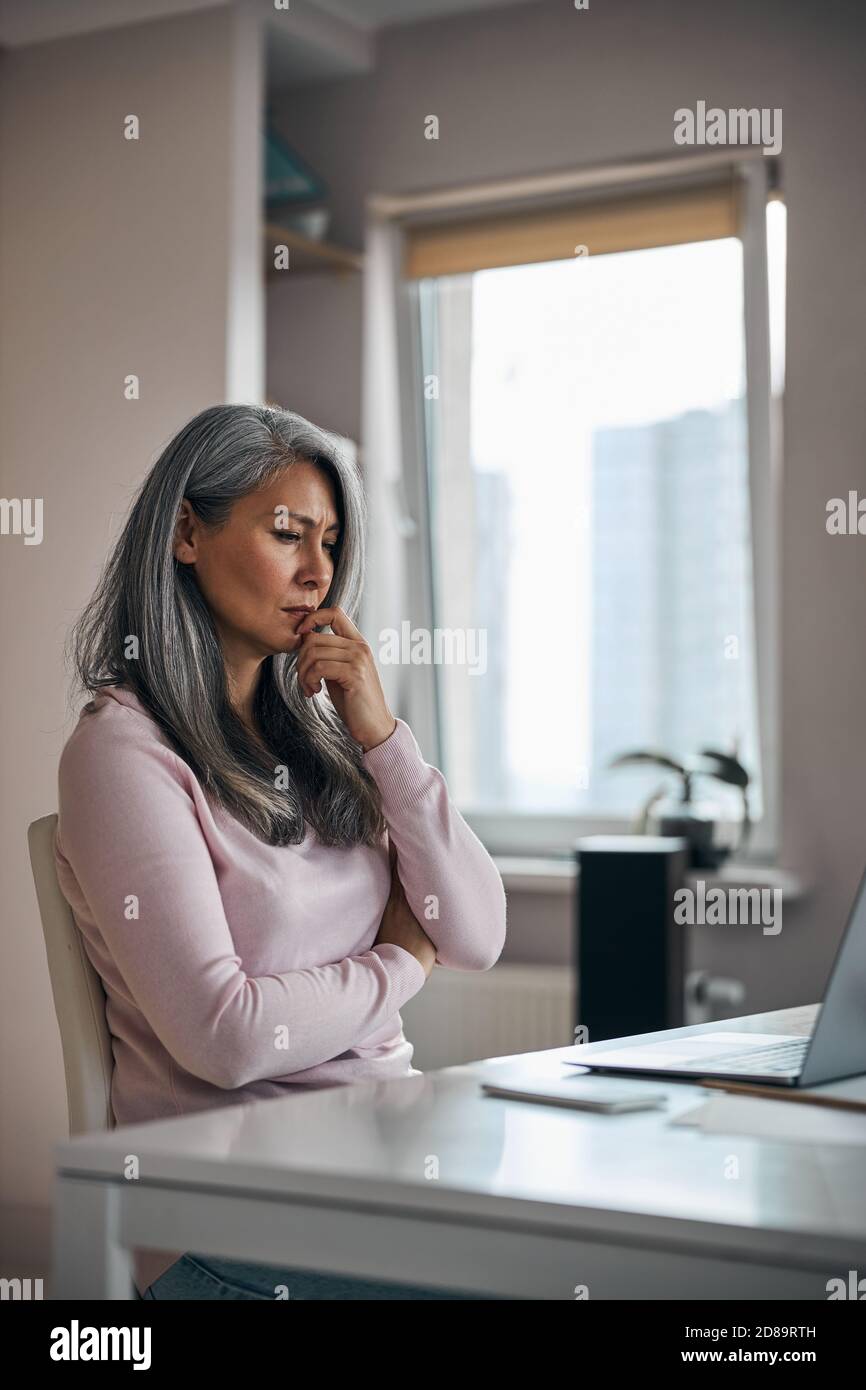 Excited woman in blush sweater thinking of something while sitting at ...