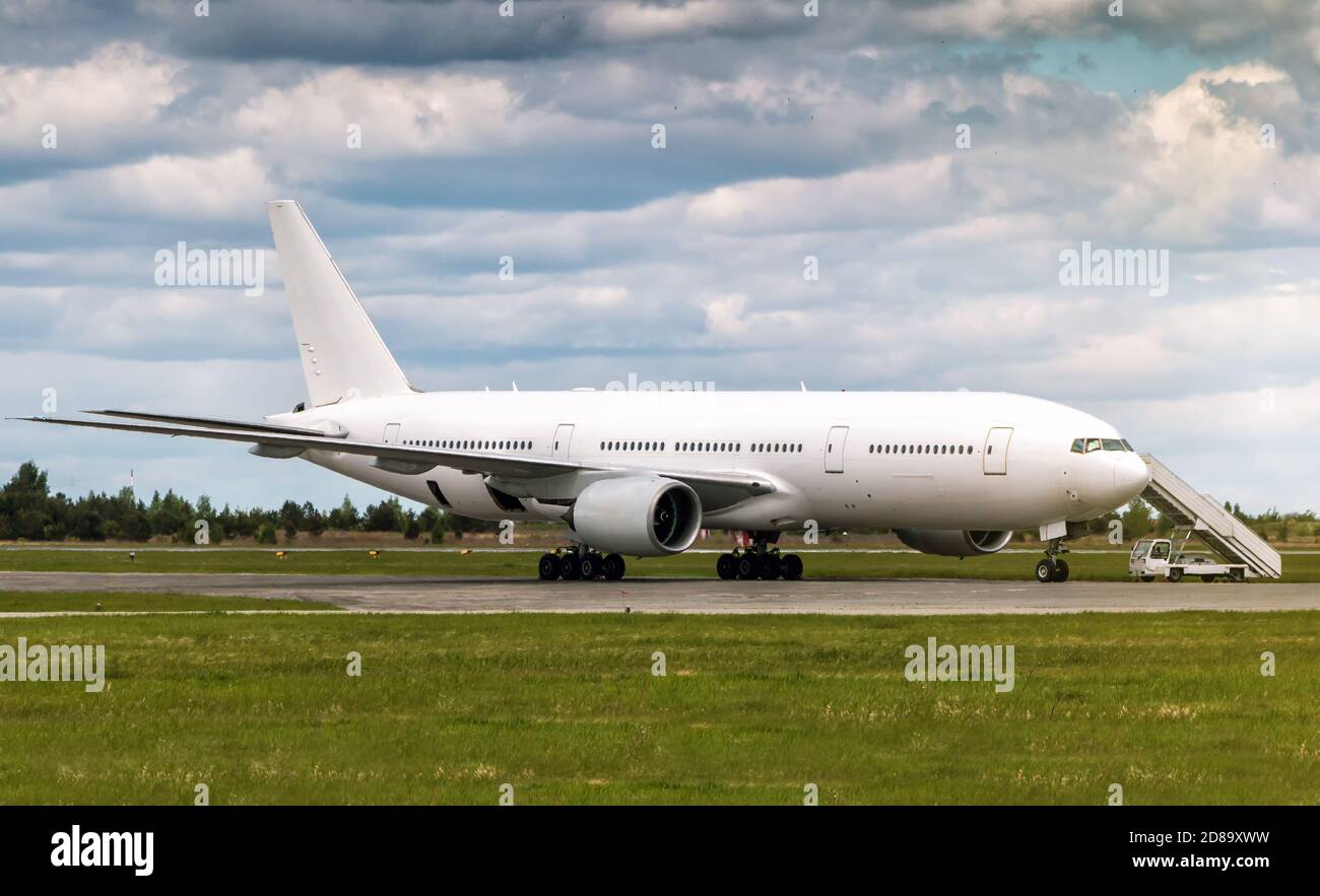 Wide body passenger airplane with boarding stairs at the airport apron ...