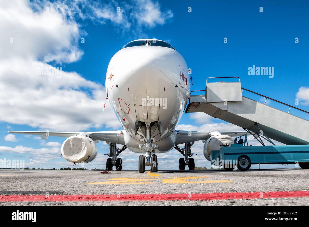 Front view of white passenger airplane with boarding ramp at the ...