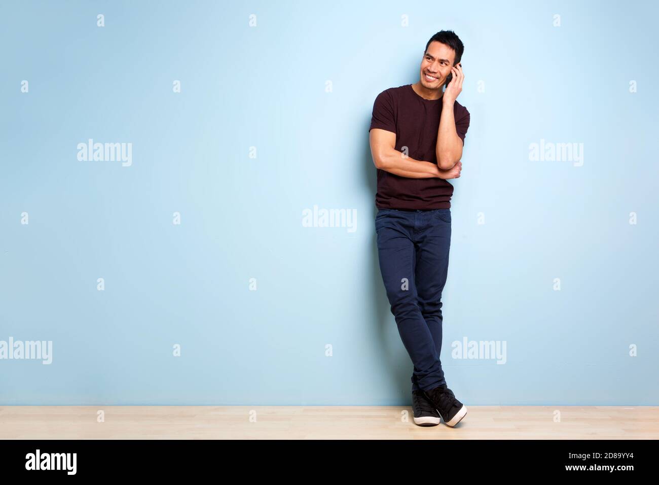 Full body portrait of stylish mature asian man standing by blue wall ...