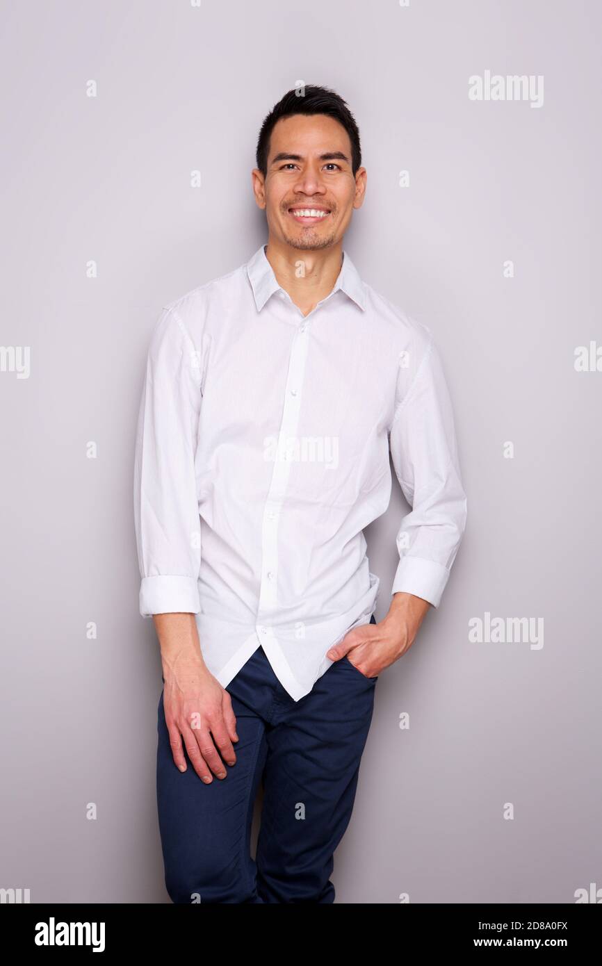 Portrait of smart middle aged asian man standing relaxed over gray ...